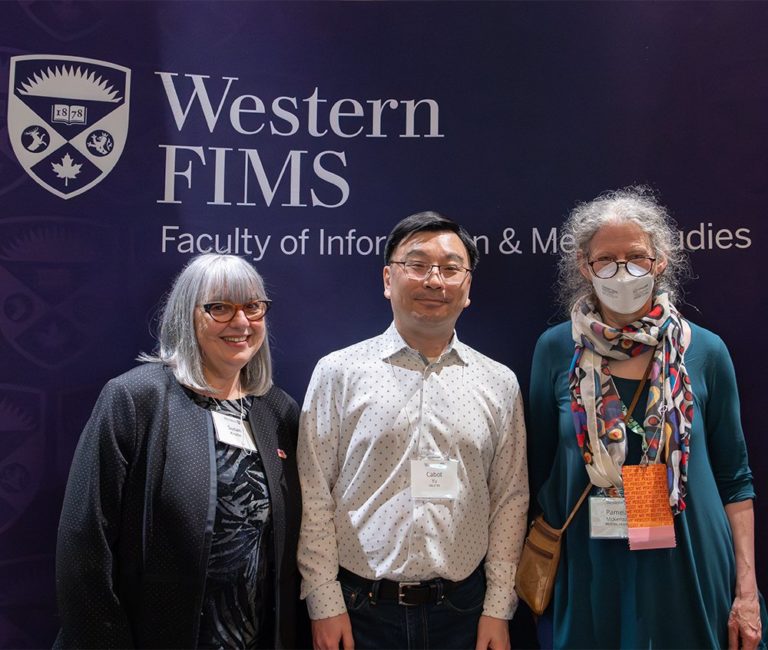 Three People Smiling At Camera In Front Of Fims Backdrop | Western Alumni